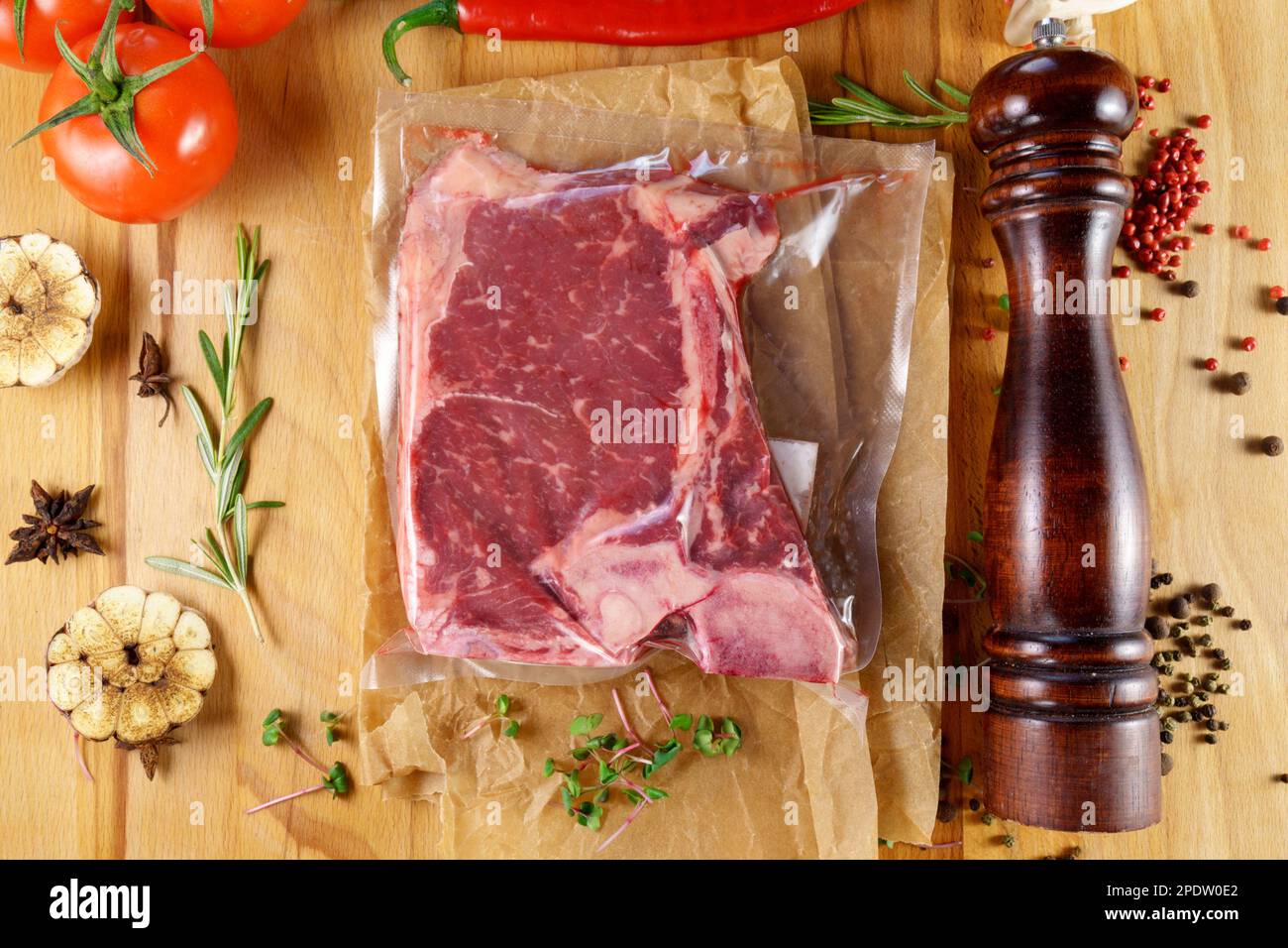 Vacuum packed meat, on a wooden board, steak. Top view. Various spices ...