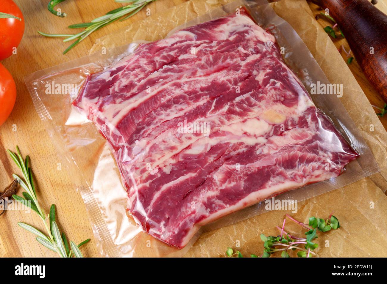 Vacuum packed meat, on a wooden board, steak. Top view. Various spices ...