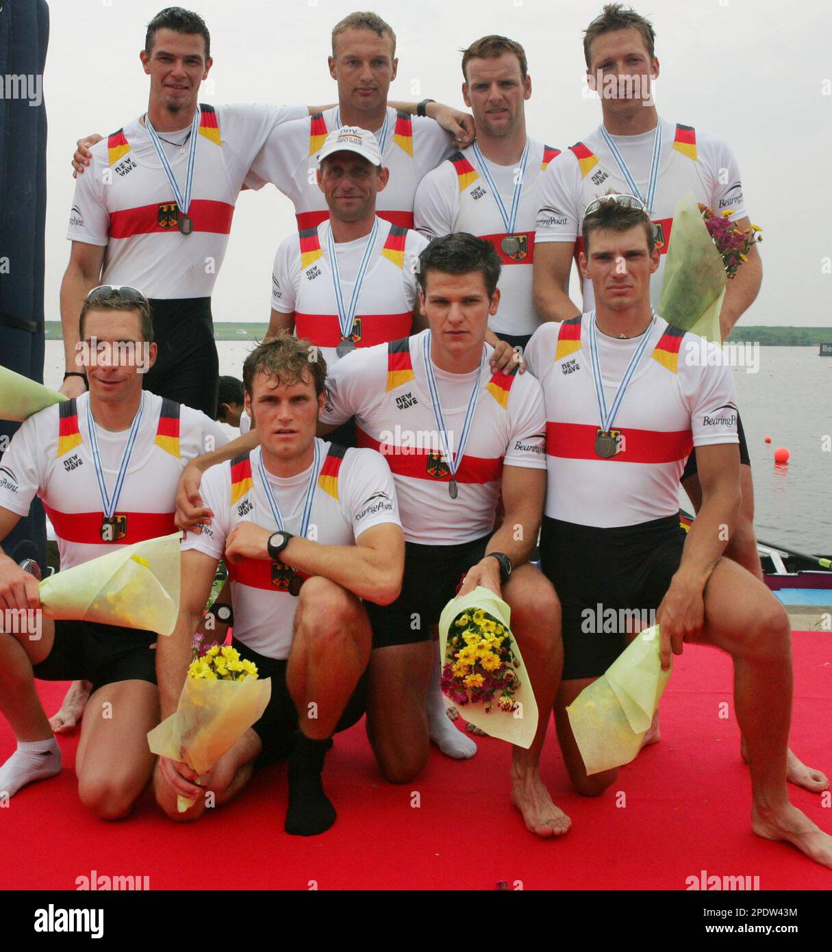 German men's eight team members pose with their bronze medals on podium ...