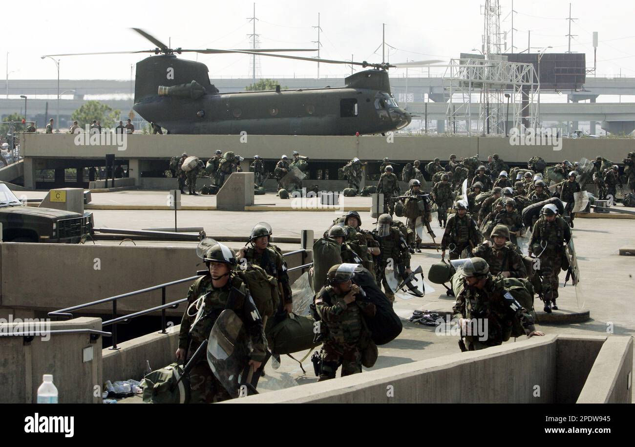 Troops disembark from a military helicopter at the Louisiana Superdome ...