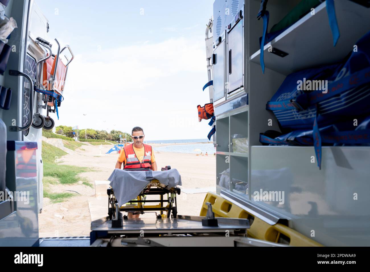 First aid worker using the stretcher of ambulance to work on the beach ...