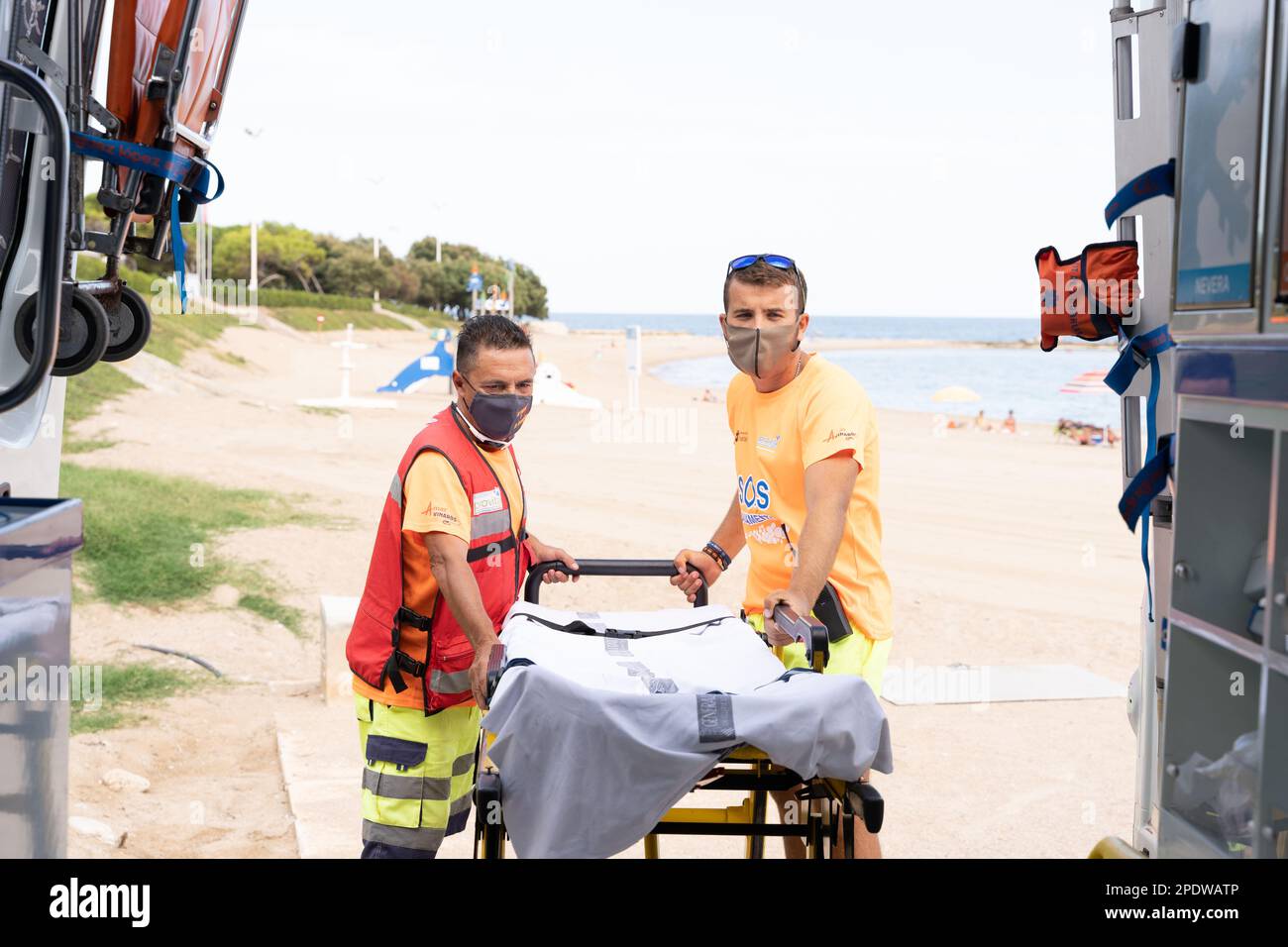 Lifeguard team working on the beach using a stretcher from an ambulance ...