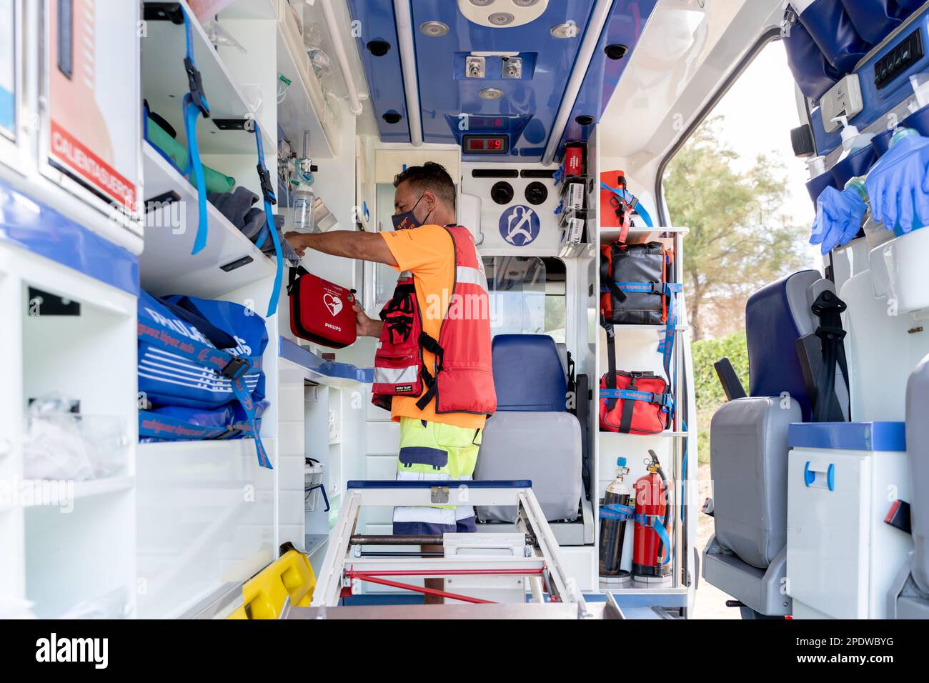 Profile of a first aid worker with mask working inside an ambulance ...
