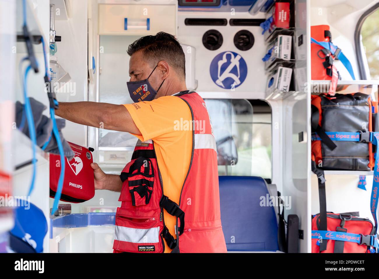 Profile of a lifeguard worker with mask working inside an ambulance ...