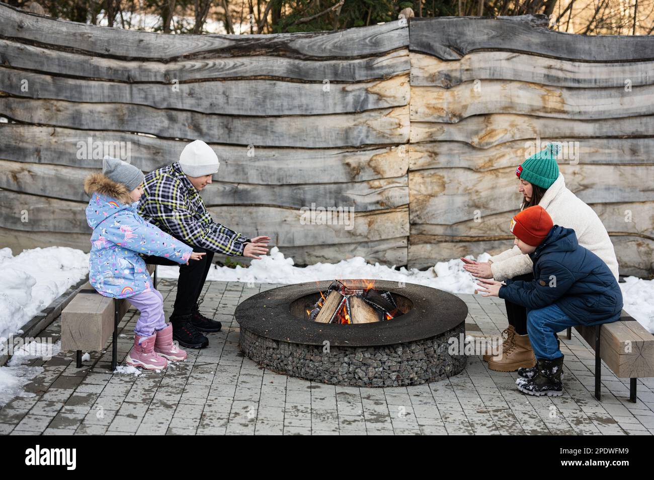 Mother with kids sitting by camp bonfire on winter in forest. Children ...
