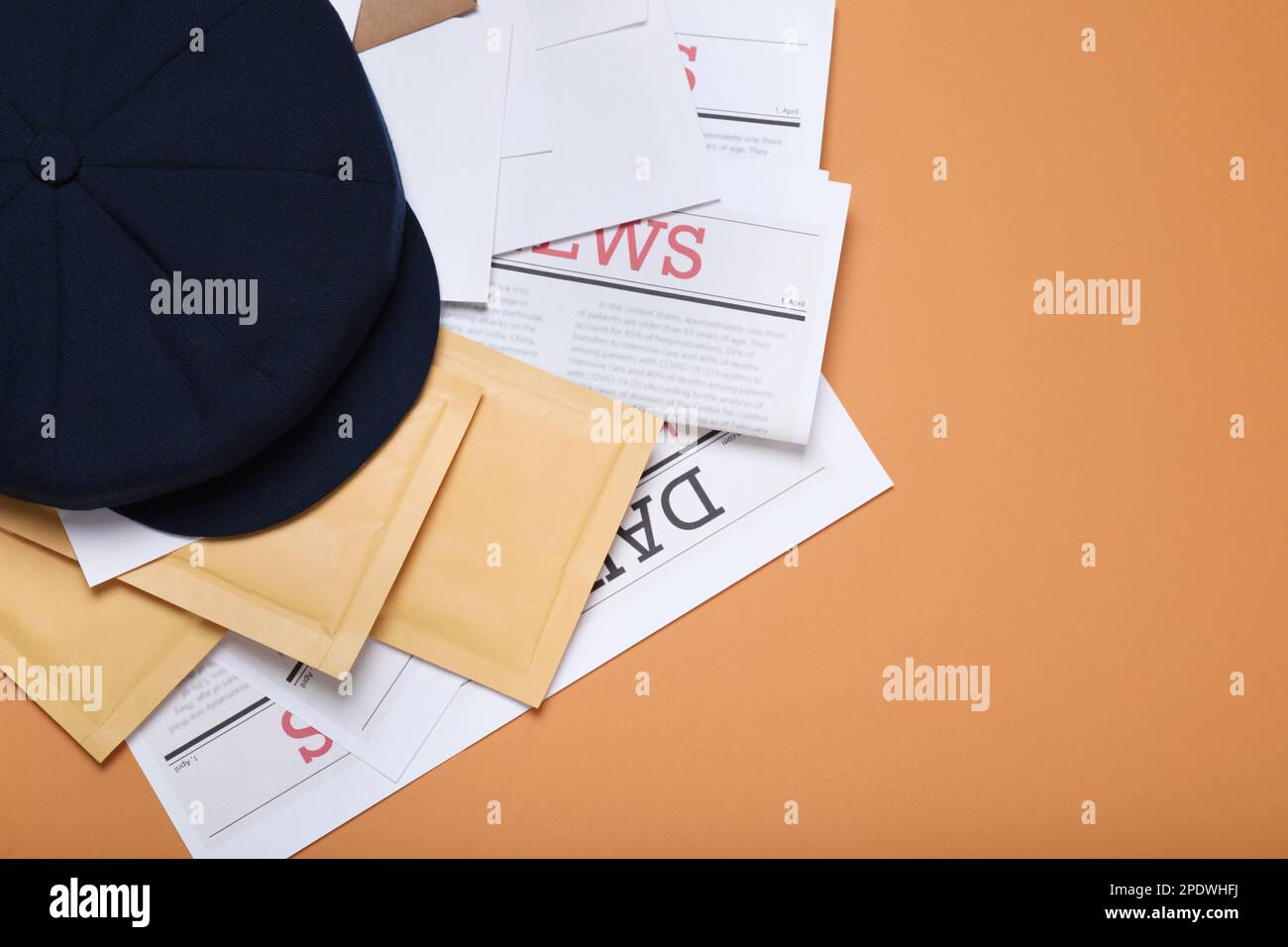 Postman hat, newspapers and mails on light brown background, flat lay ...
