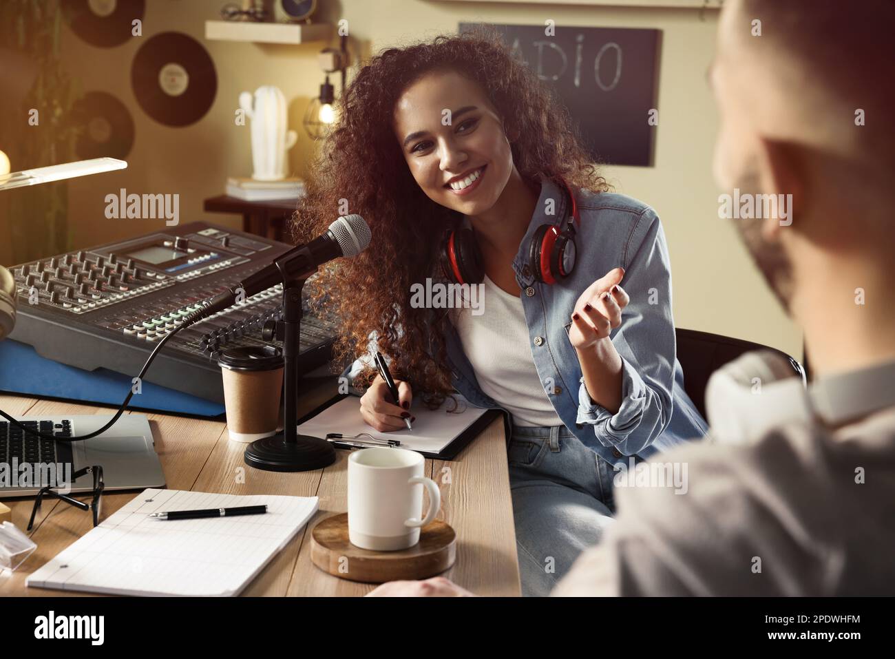 Young African American woman interviewing man in modern radio studio ...