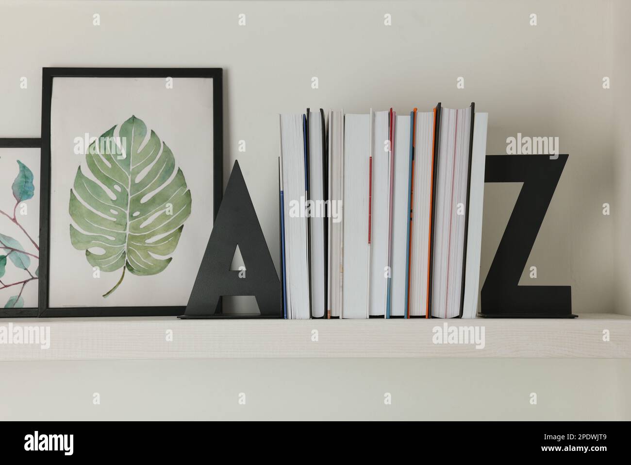 Bookends with books and pictures on shelf indoors Stock Photo - Alamy