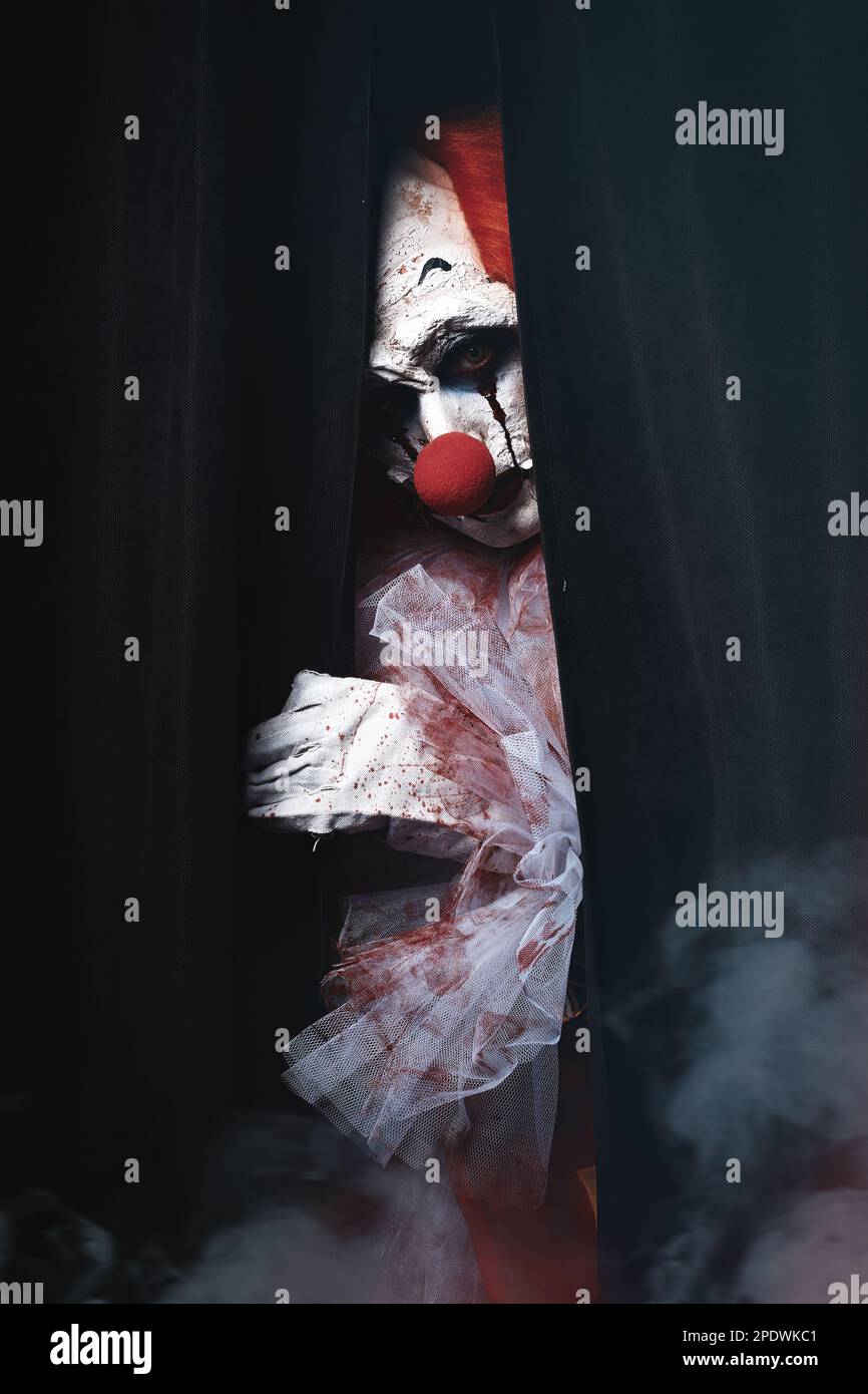 Terrifying clown hiding behind black curtains. Halloween party costume ...