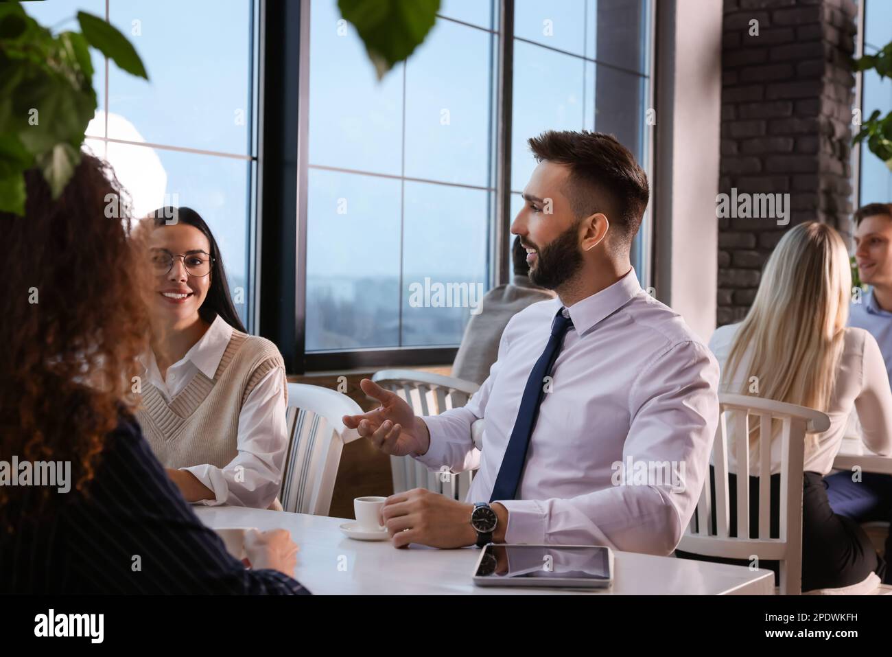 Coworkers having coffee break near window in cafe Stock Photo - Alamy