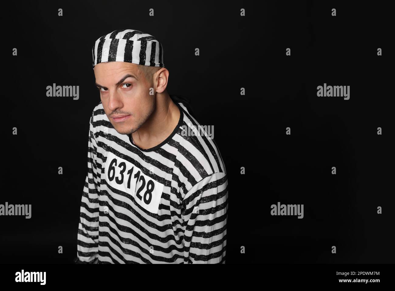 Prisoner in striped uniform on black background, space for text Stock ...