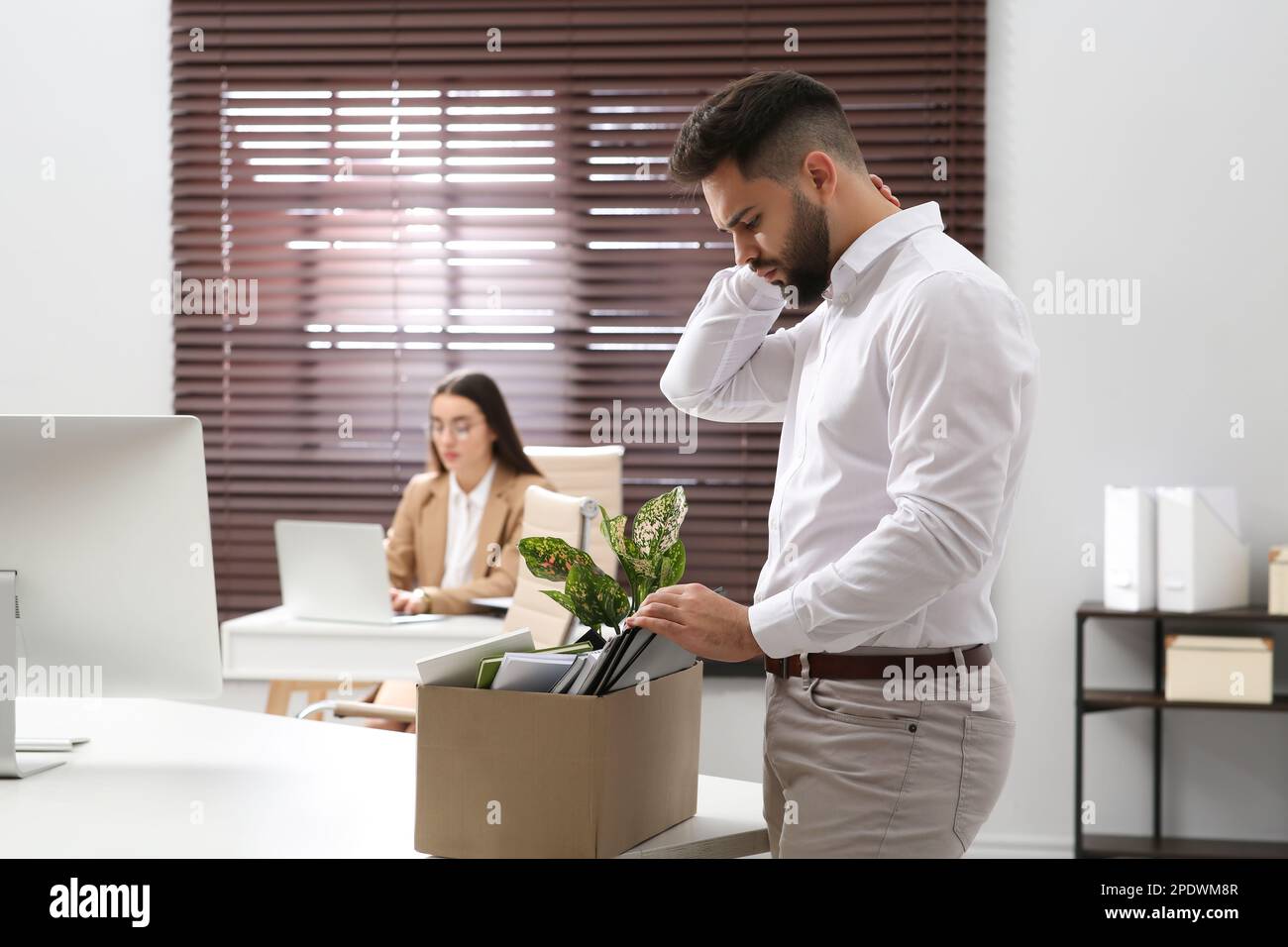 Dismissed man packing personal stuff into box in office Stock Photo - Alamy
