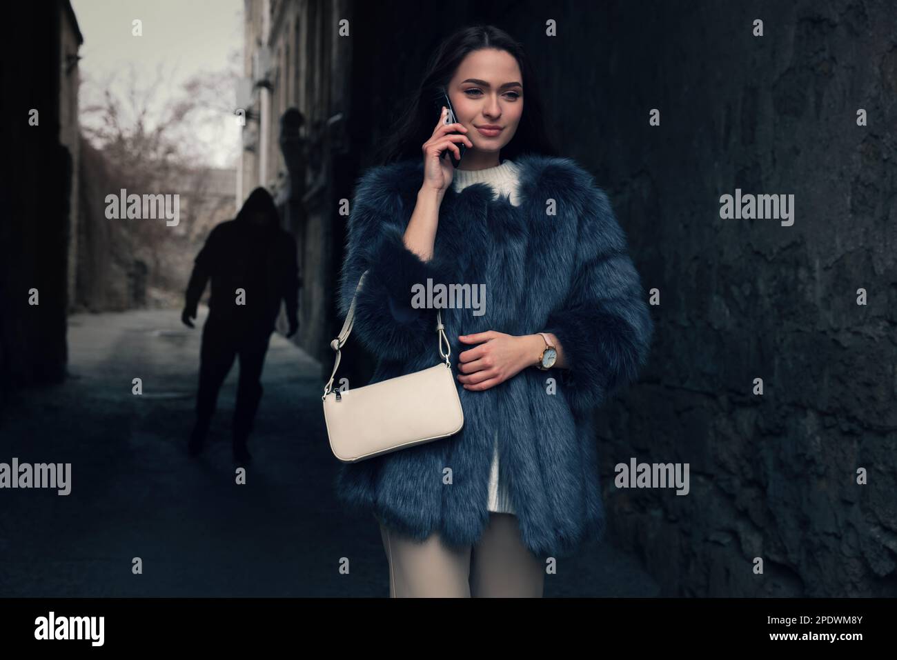 Man stalking young woman while she talking on phone in alley Stock ...