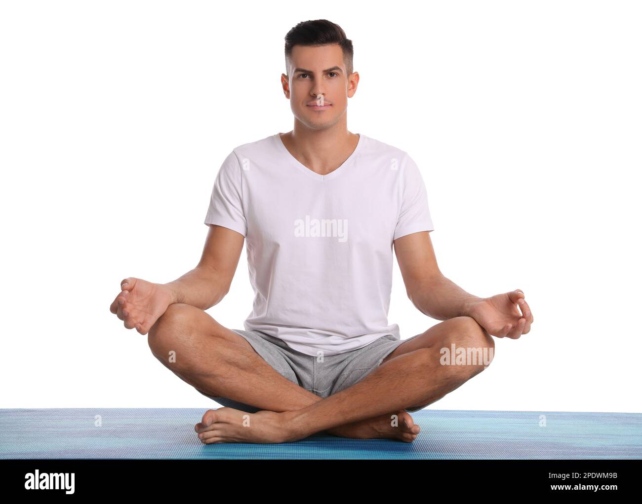 Handsome man meditating on yoga mat against white background Stock ...