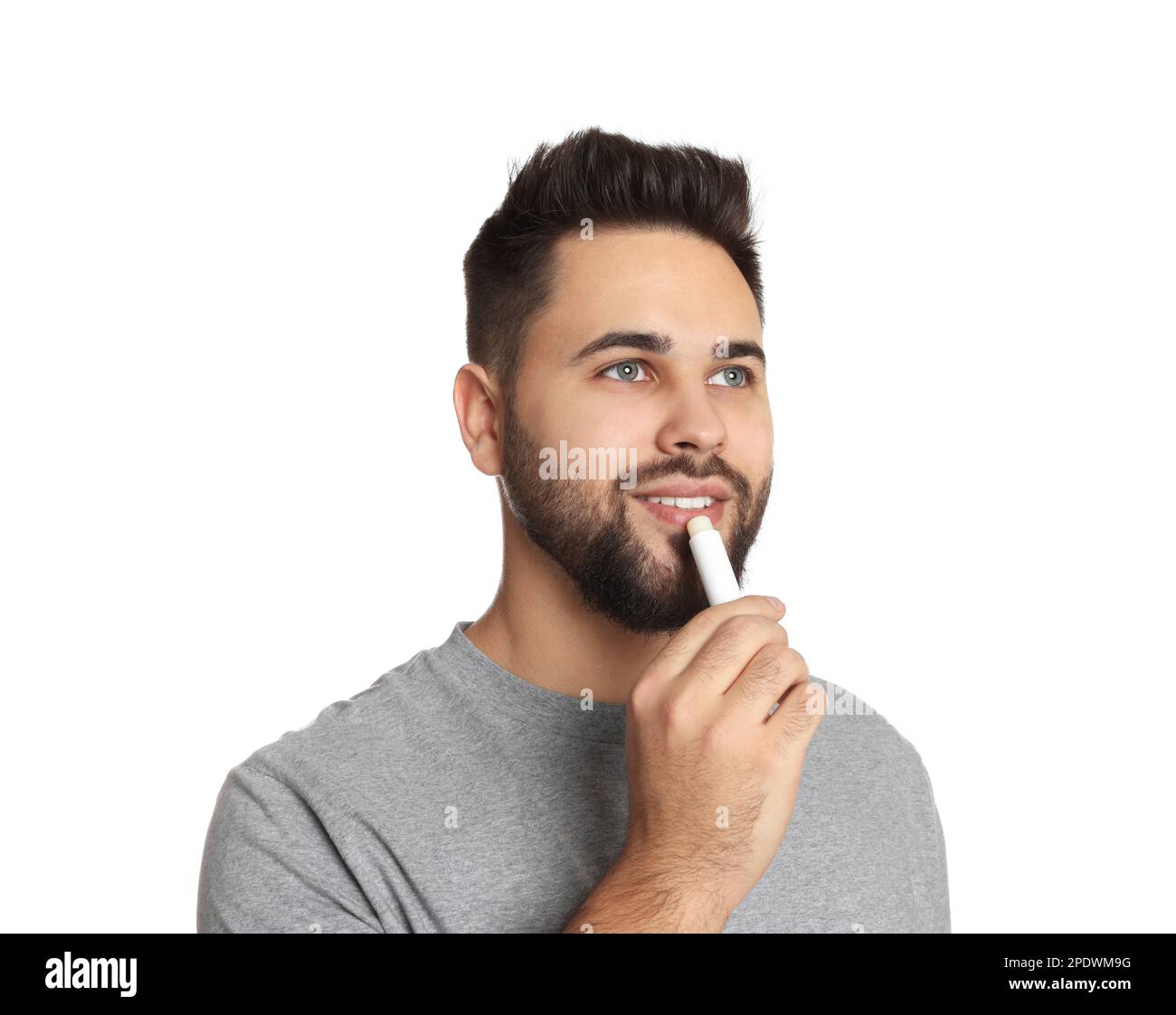Young man applying lip balm on white background Stock Photo - Alamy