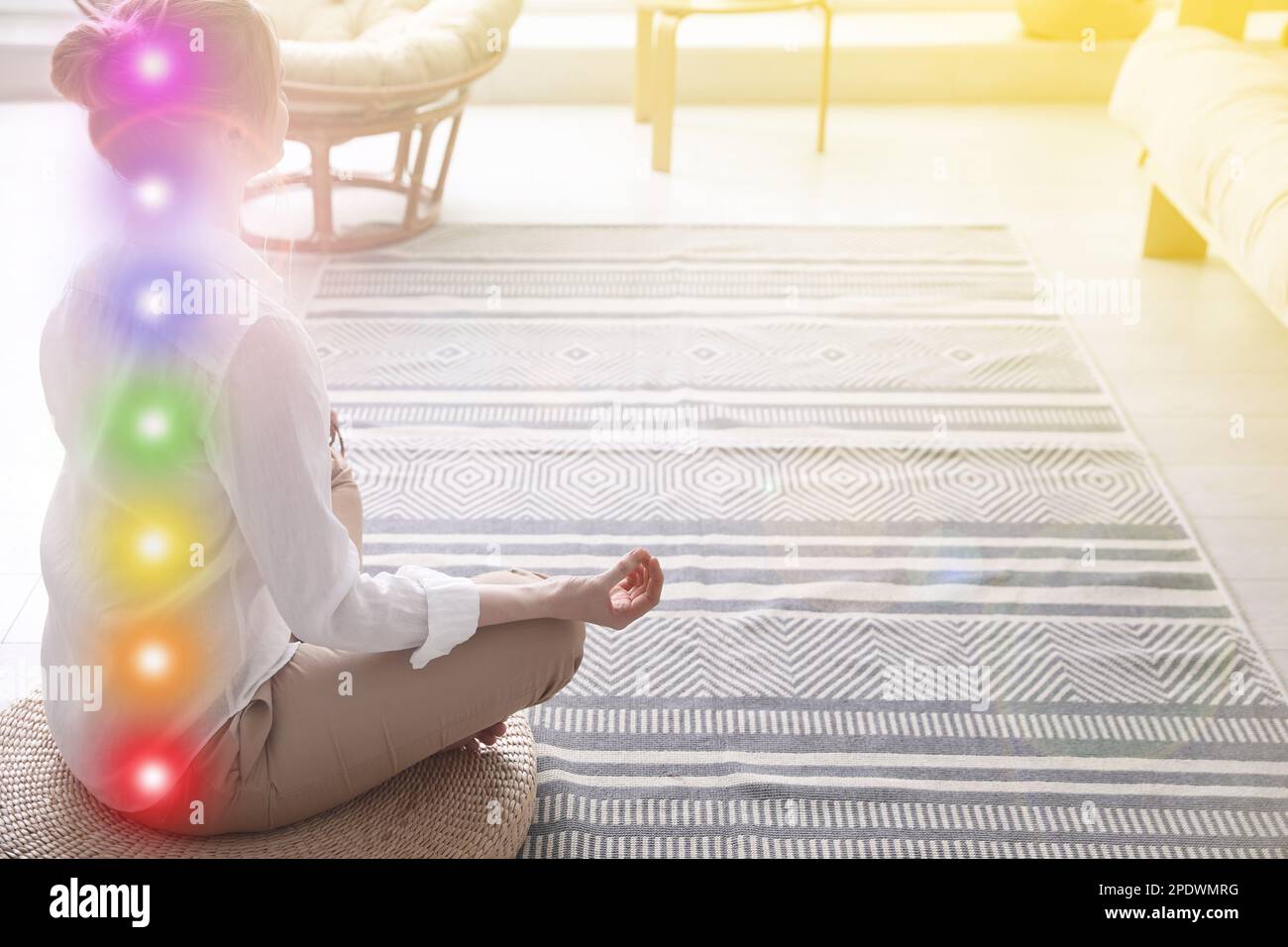 Woman meditating on wicker mat at home. Scheme of seven chakras ...
