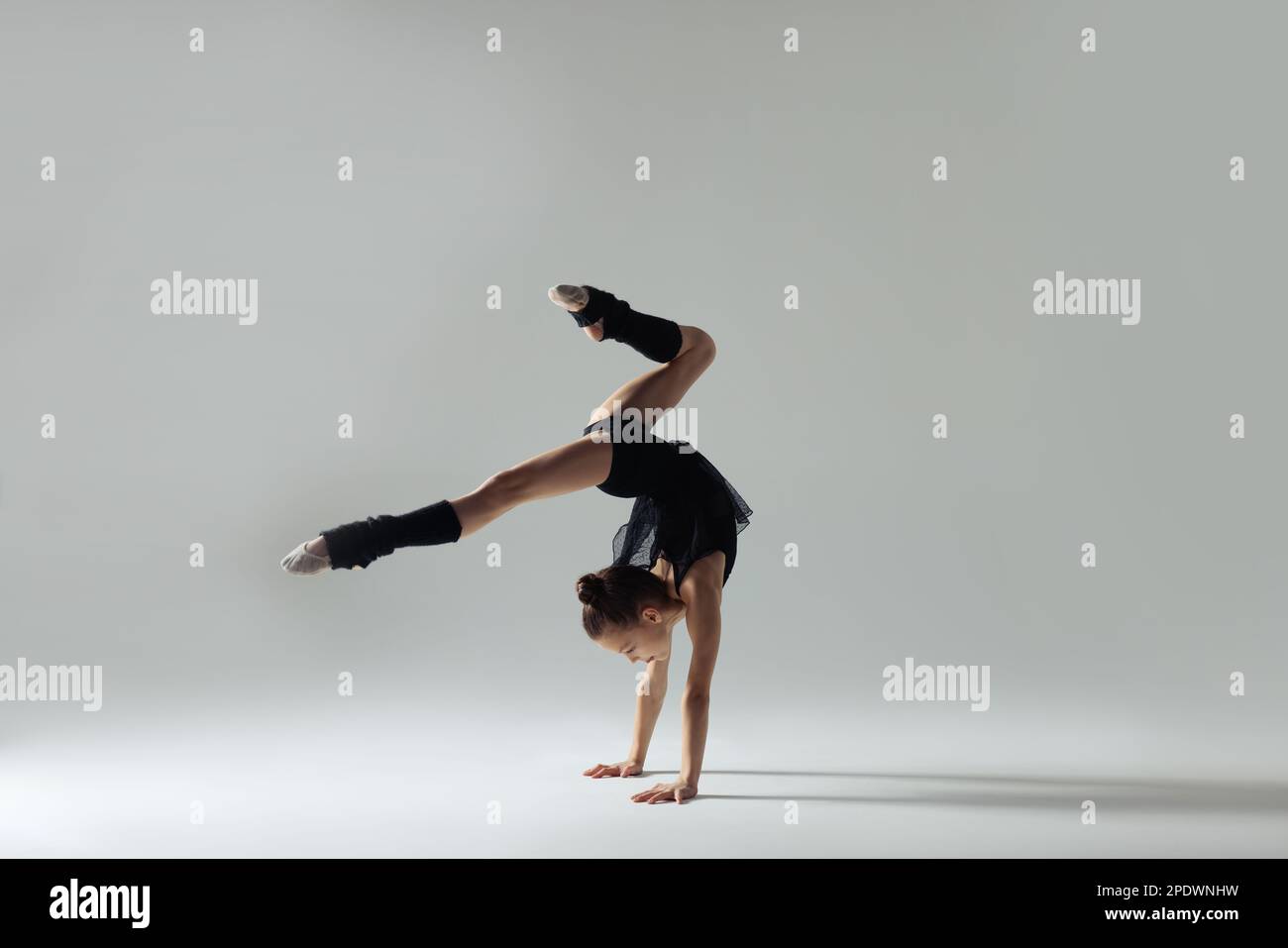 Cute little gymnast doing handstand on white background Stock Photo - Alamy