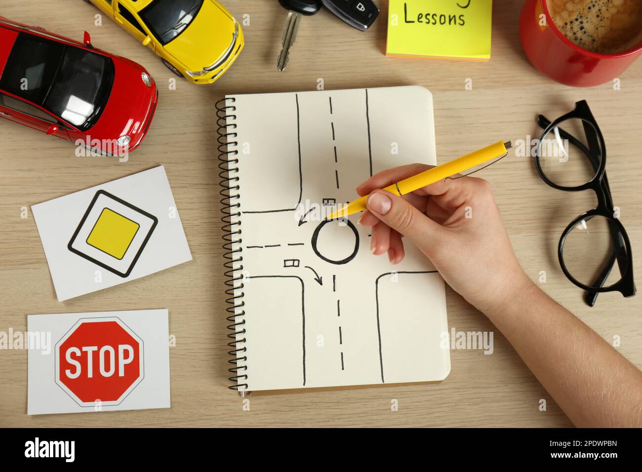 Woman with workbook for driving lessons and road signs at wooden table ...