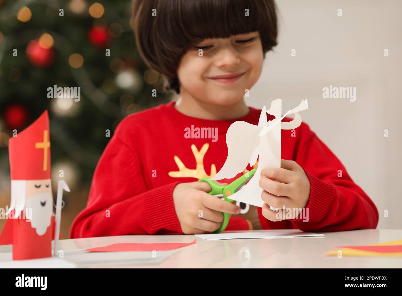 Cute little boy making paper angel for Saint Nicholas day at home ...