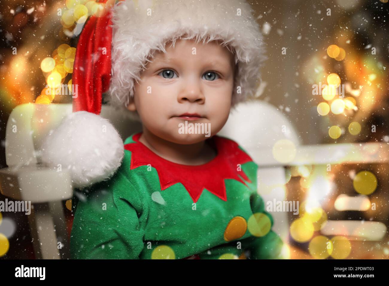 Baby in cute elf costume sitting on chair at home. Christmas ...