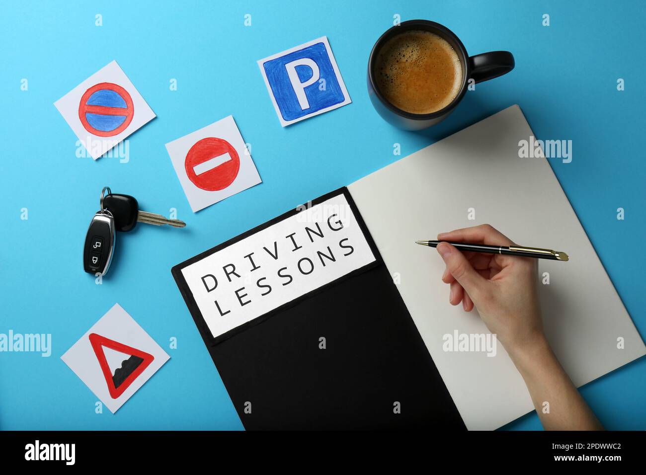 Woman with workbook for driving lessons on light blue background, top ...