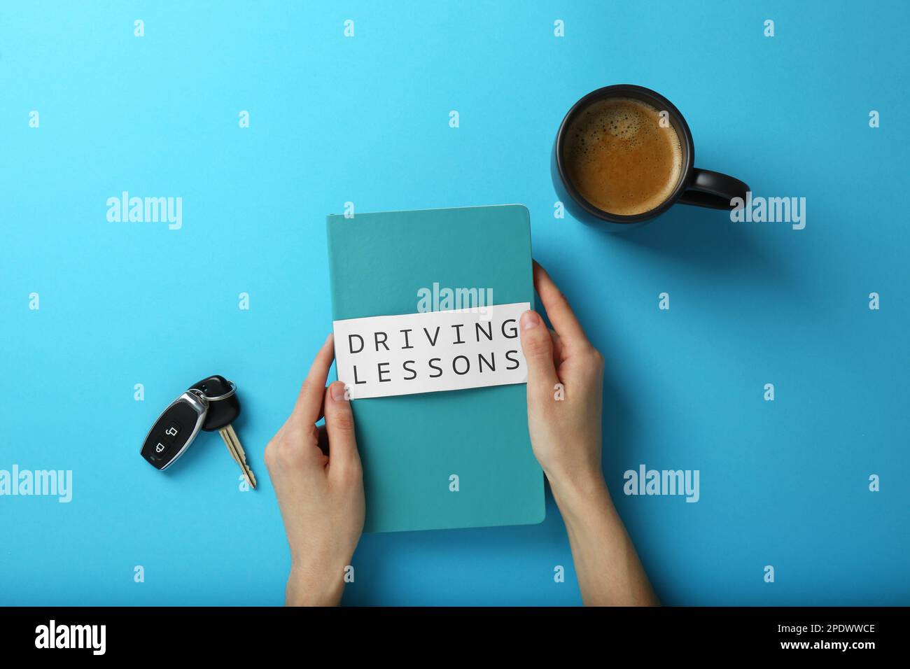 Woman with workbook for driving lessons on light blue background, top ...