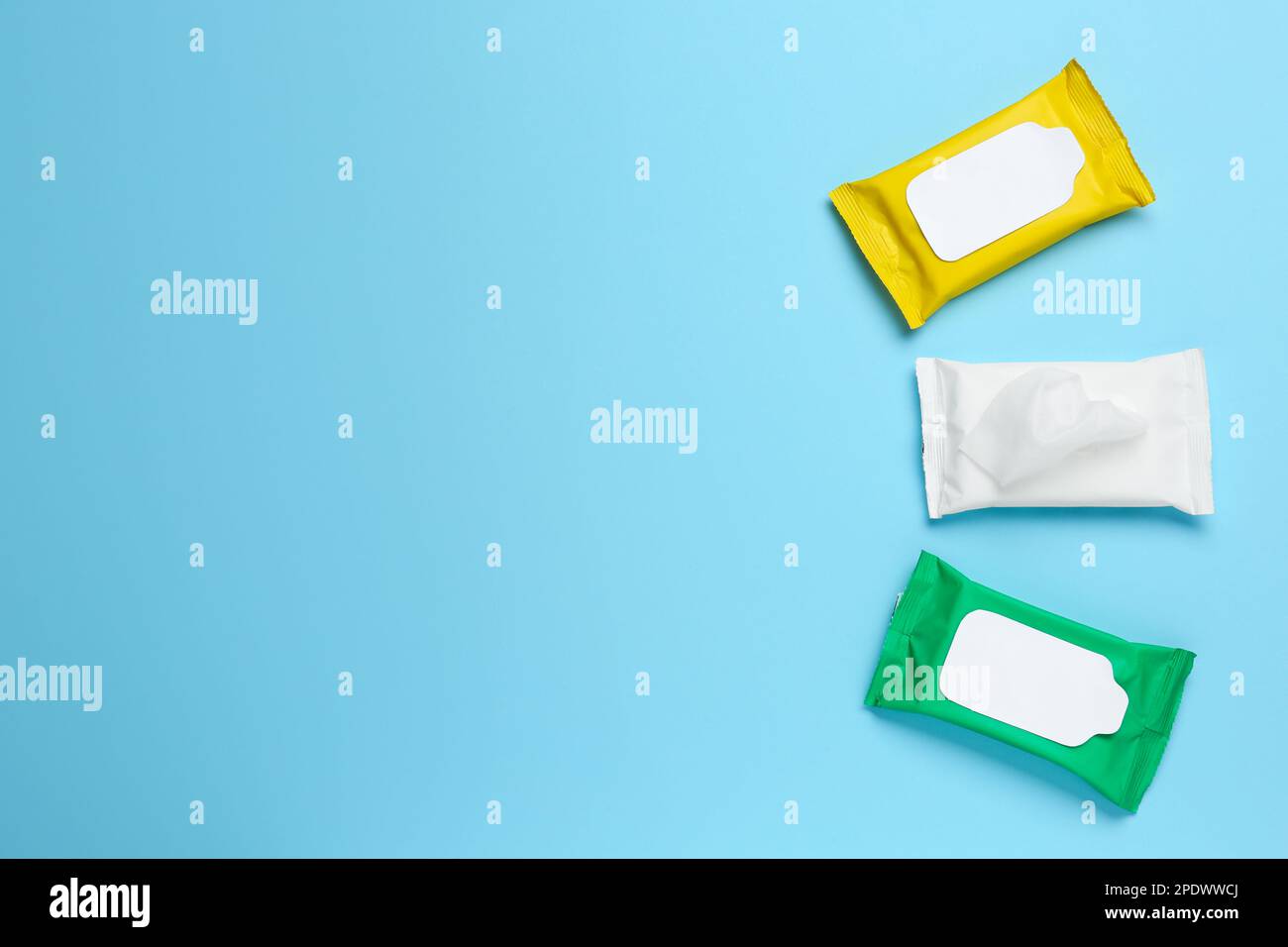 Wet wipes flow packs on light blue background, flat lay. Space for text ...