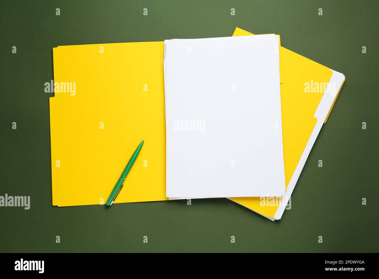 Yellow files with blank sheets of paper and pen on dark green ...