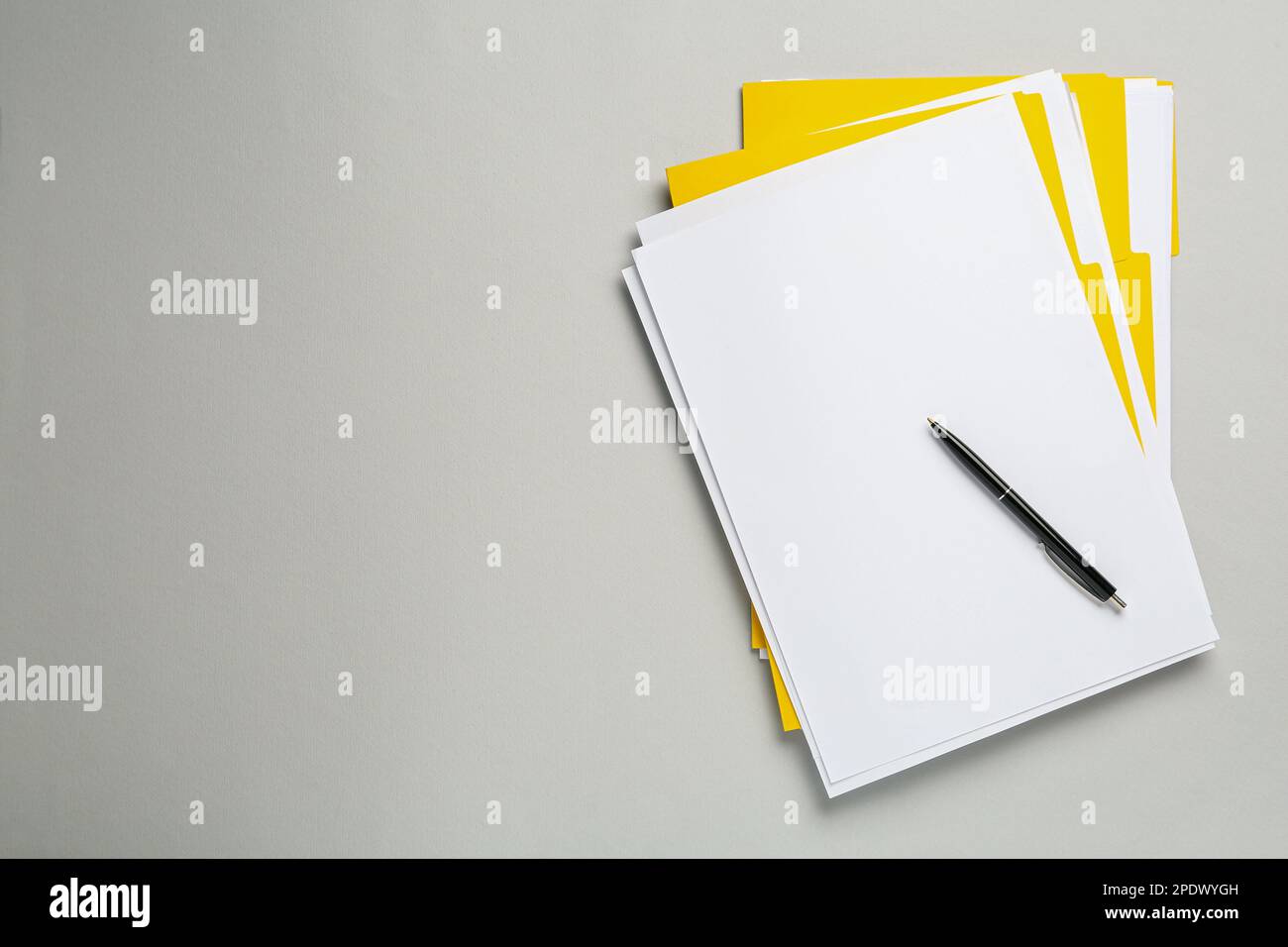 Yellow files with blank sheets of paper and pen on light grey ...