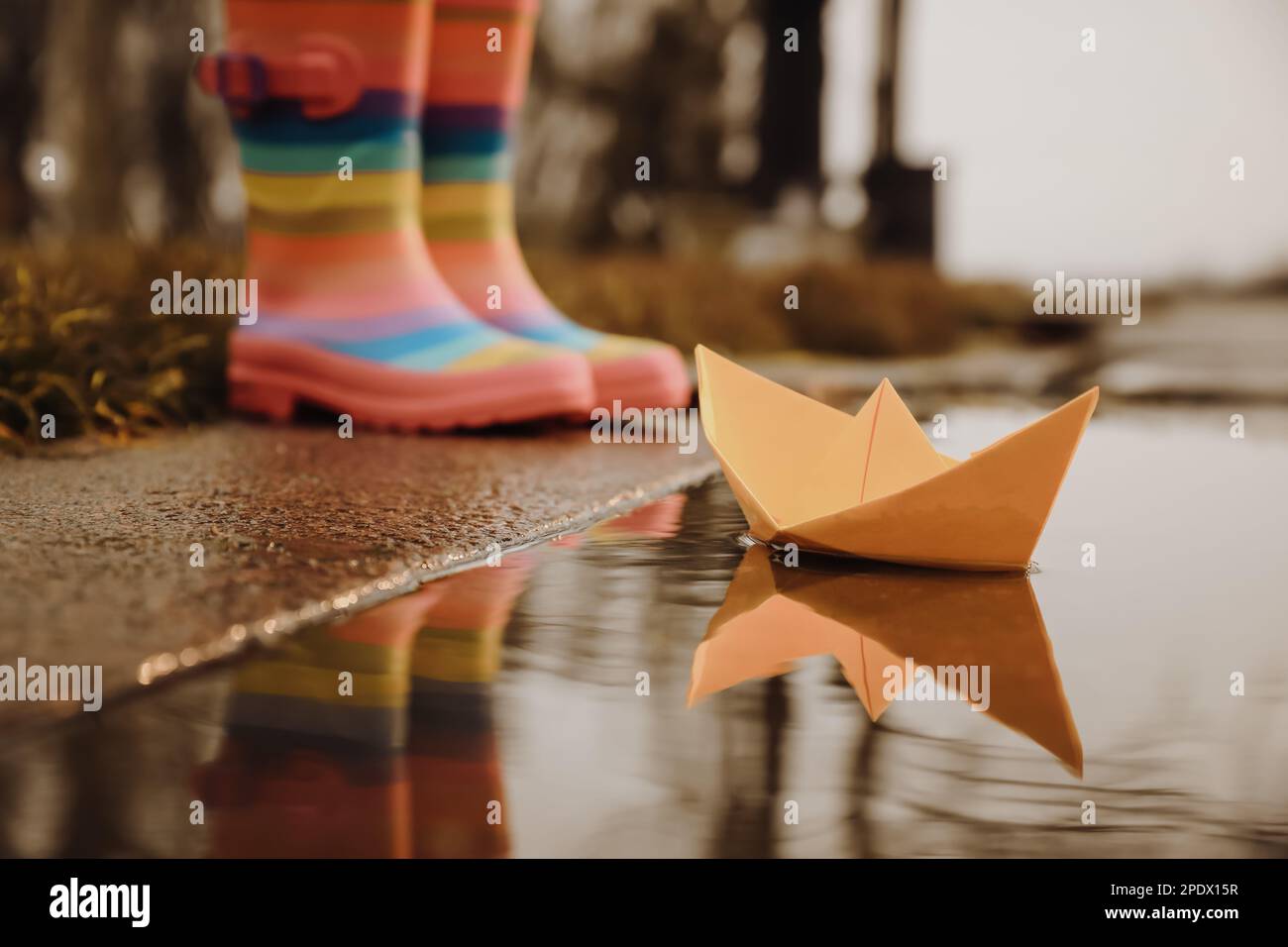 Little girl outdoors, focus on paper boat in puddle Stock Photo - Alamy
