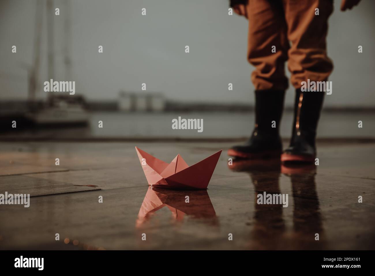 Little boy outdoors, focus on paper boat in puddle Stock Photo - Alamy