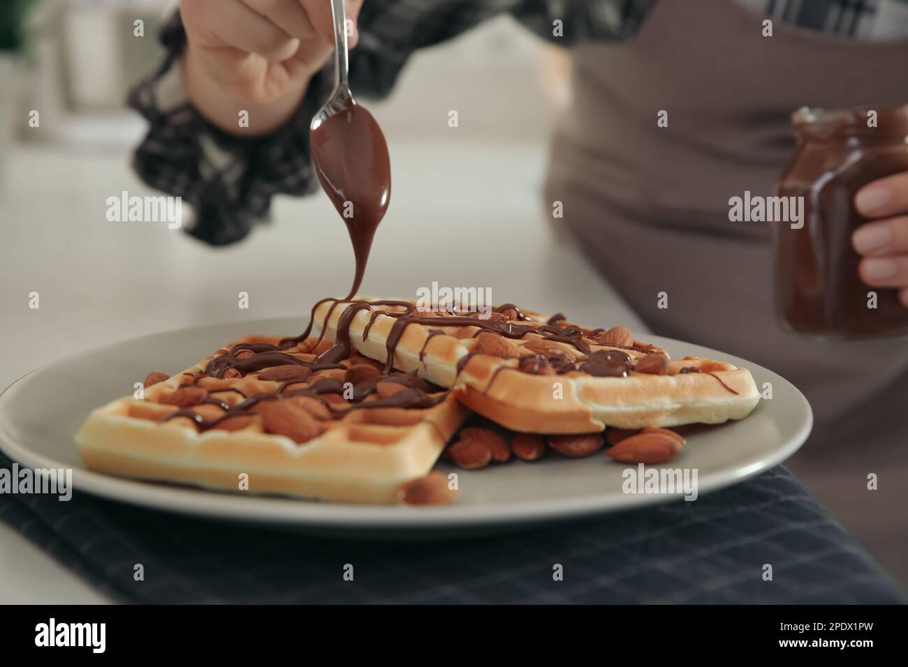 Woman decorating delicious Belgian waffles with chocolate cream at ...
