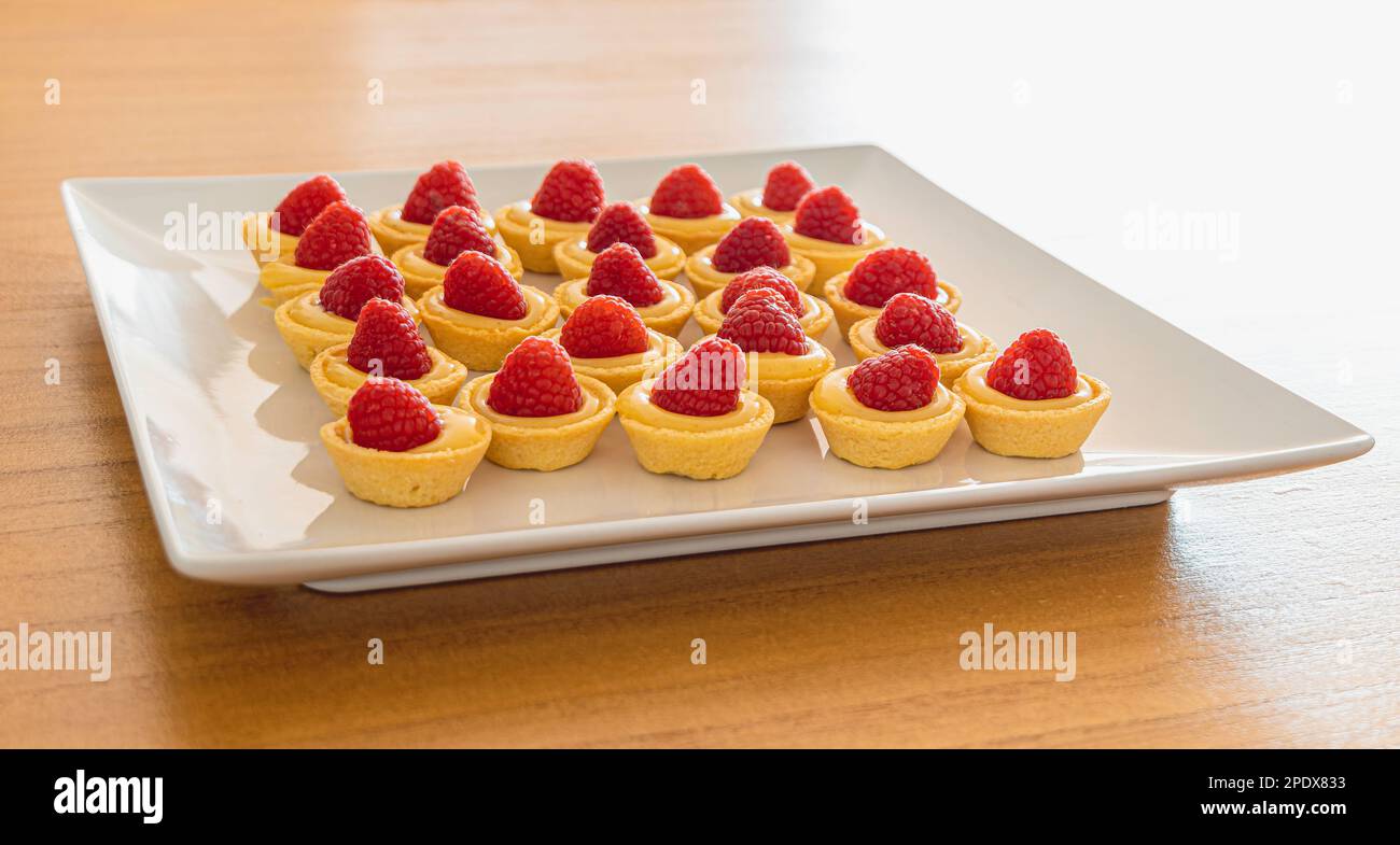 Raspberry tartlets with lemon curd on a white plate. Elegant pastry ...