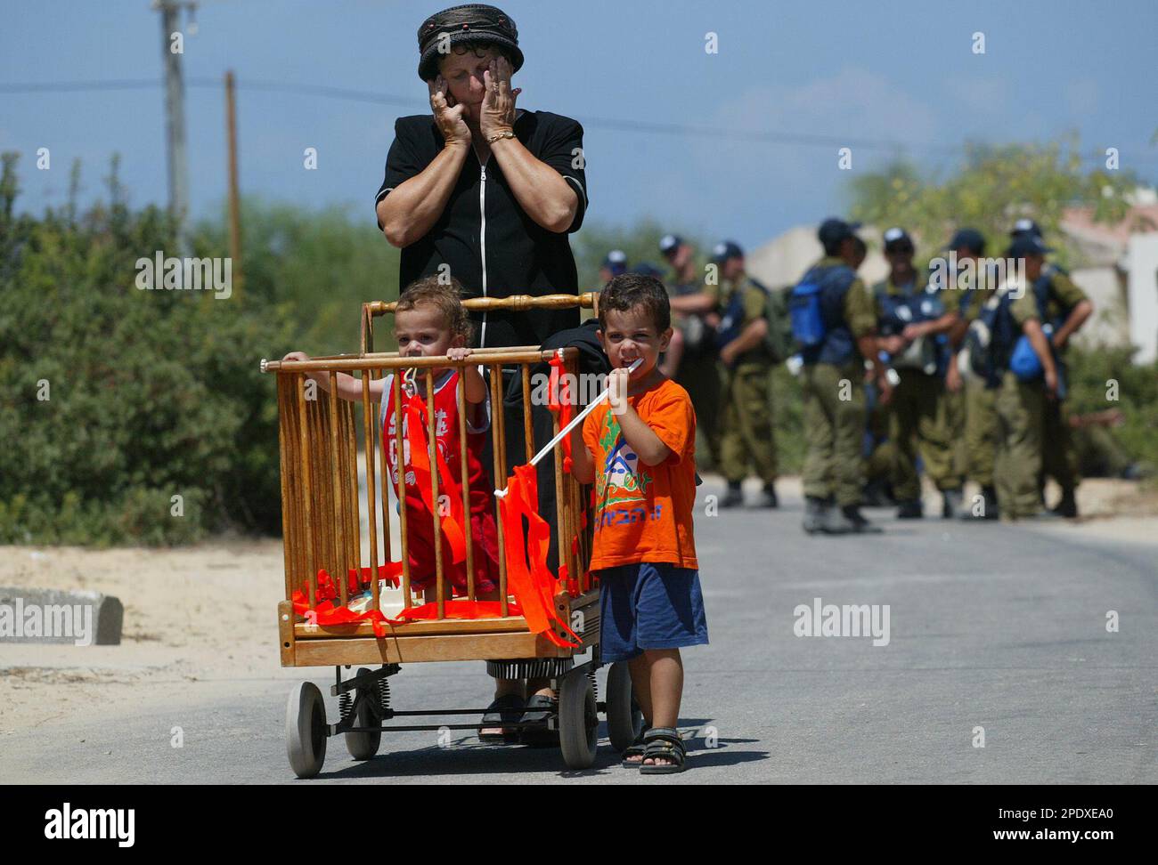 A settler walks with two children as Israeli soldiers and border police ...