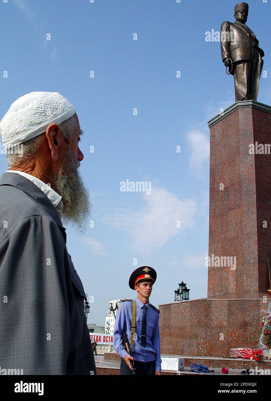 An elderly man wearing a traditional Chechen hat stands near a police ...