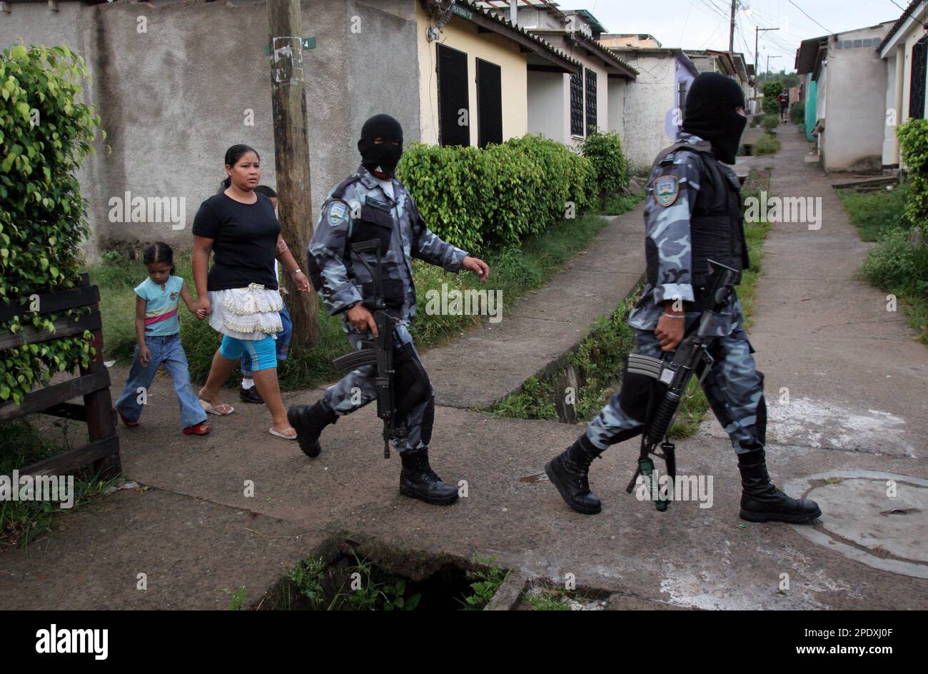 Honduran police officers wearing masks and pedestrians walk in a ...