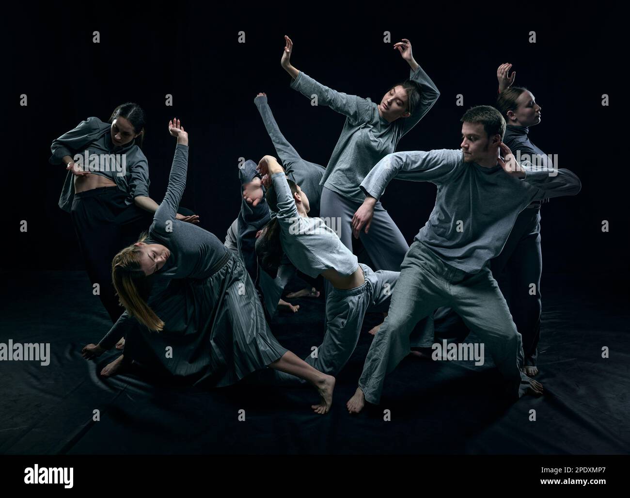 Chaos inside. Group of artistic young people dancing against black studio background. Concept of ...