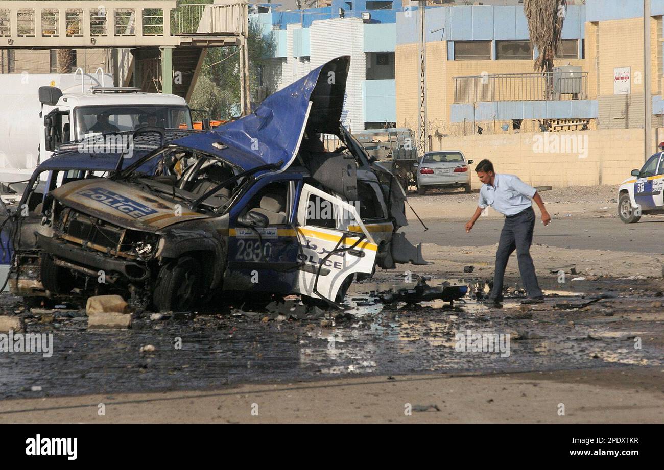 An Iraqi police officer inspects wreckage from two massive car bombs ...