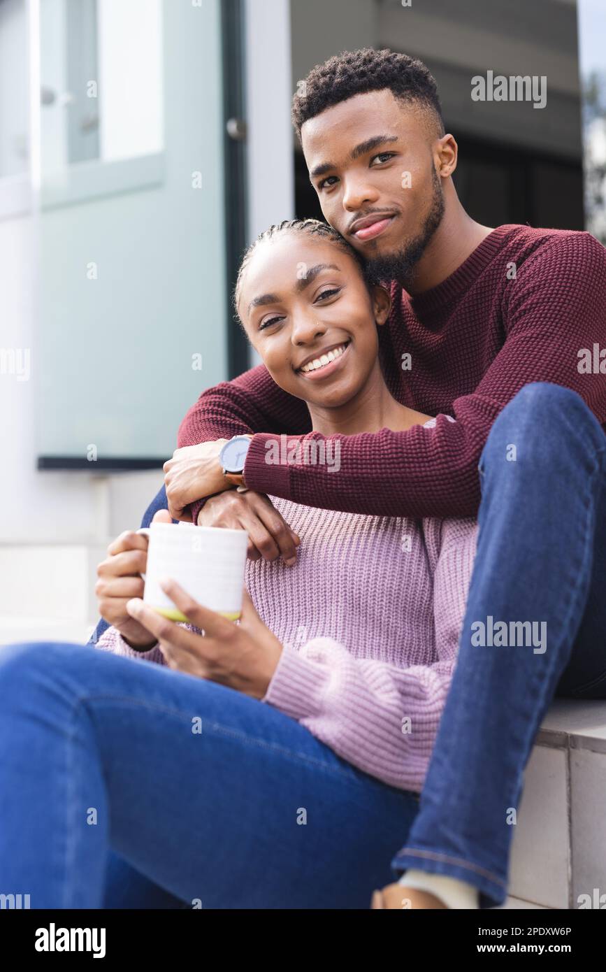 Portrait of happy african american couple sitting on stairs in garden ...