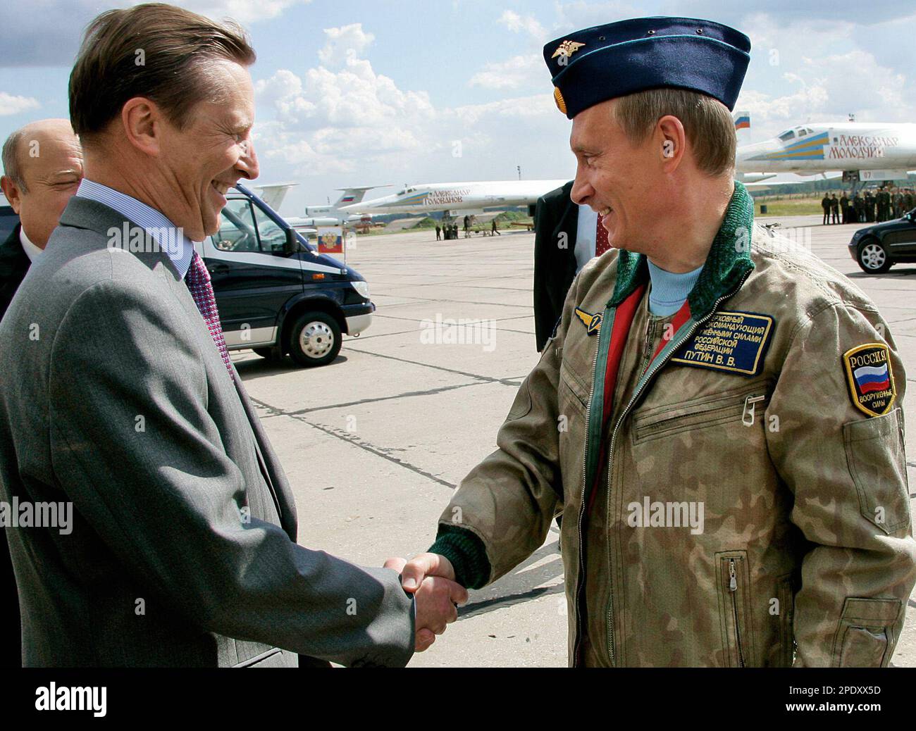 Russian President Vladimir Putin wearing a jump suit shakes hands with ...