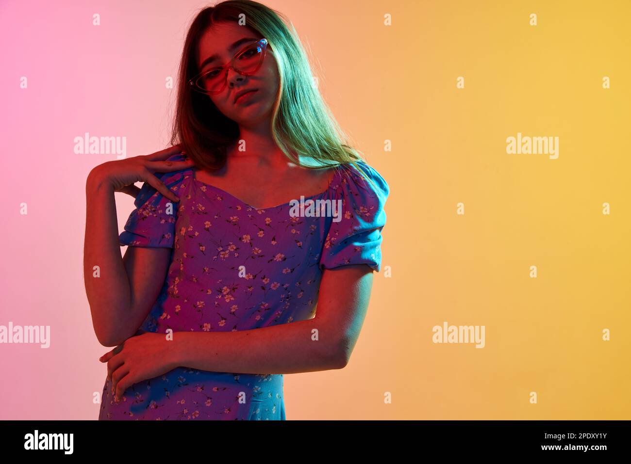 Bored dreamly girl with long hair touching shoulders with hands wearing ...