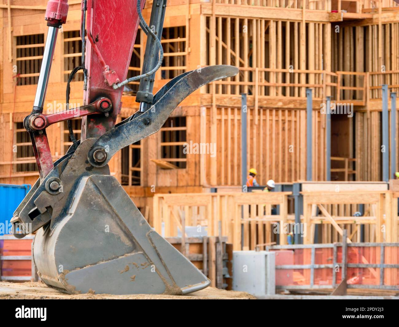 Metal excavator bucket on low-rise building construction background ...