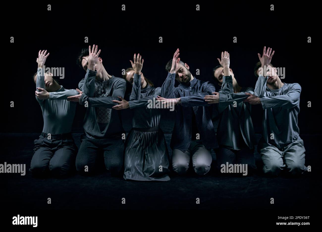 Standing on knees. Group of young artistic people dancing contemp style ...