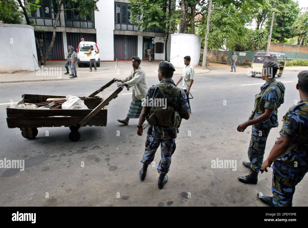 Sri Lankan government soldiers stand guard as a man pushes his cart at an intersection in ...