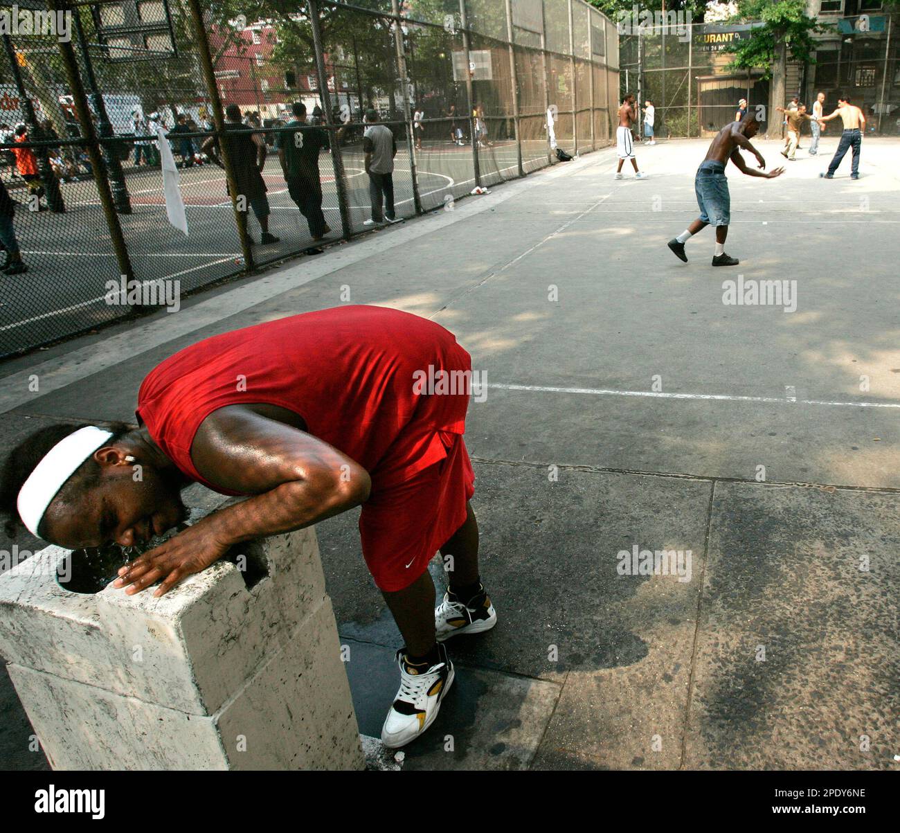 Larry Dubois, front, uses a water fountain to cool down between ...