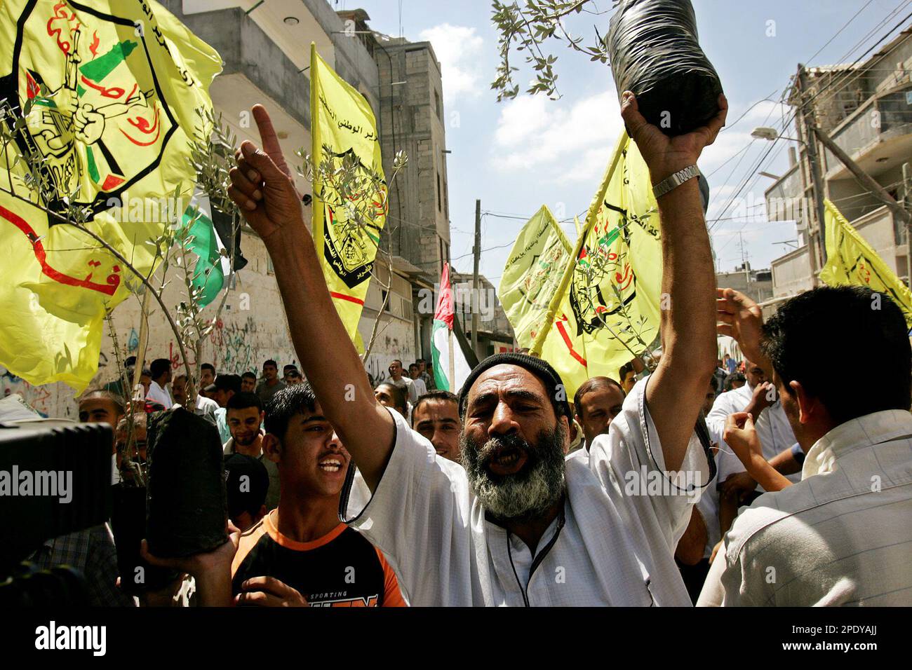Palestinians hold Fatah movement flags and olive trees during a ...