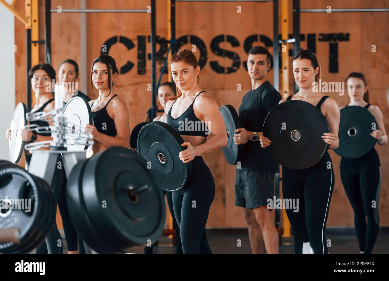 Holding weights. Group of young sportive people have crossfit day ...