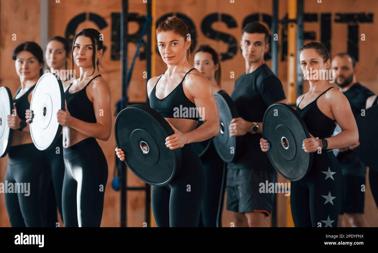 Holding weights. Group of young sportive people have crossfit day ...