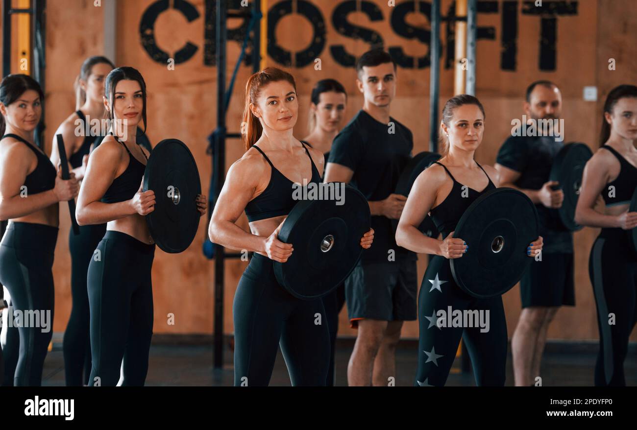 Holding weights. Group of young sportive people have crossfit day ...