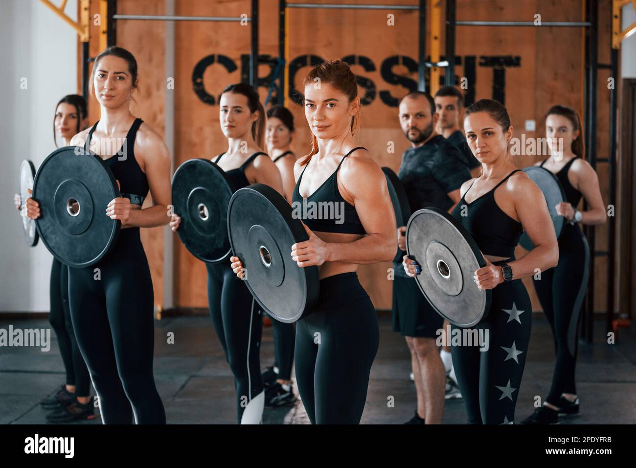 Holding weights. Group of young sportive people have crossfit day ...